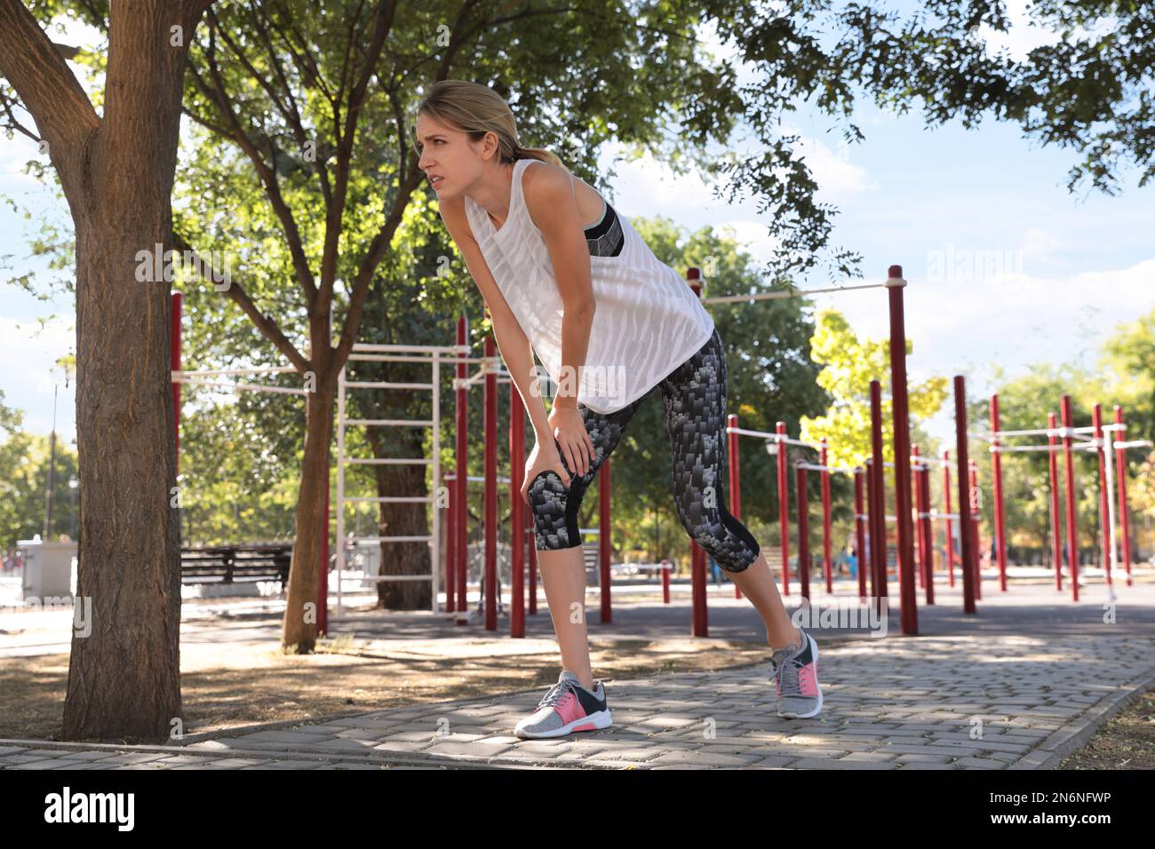 Young woman in sportswear having knee problems on sports ground Stock ...