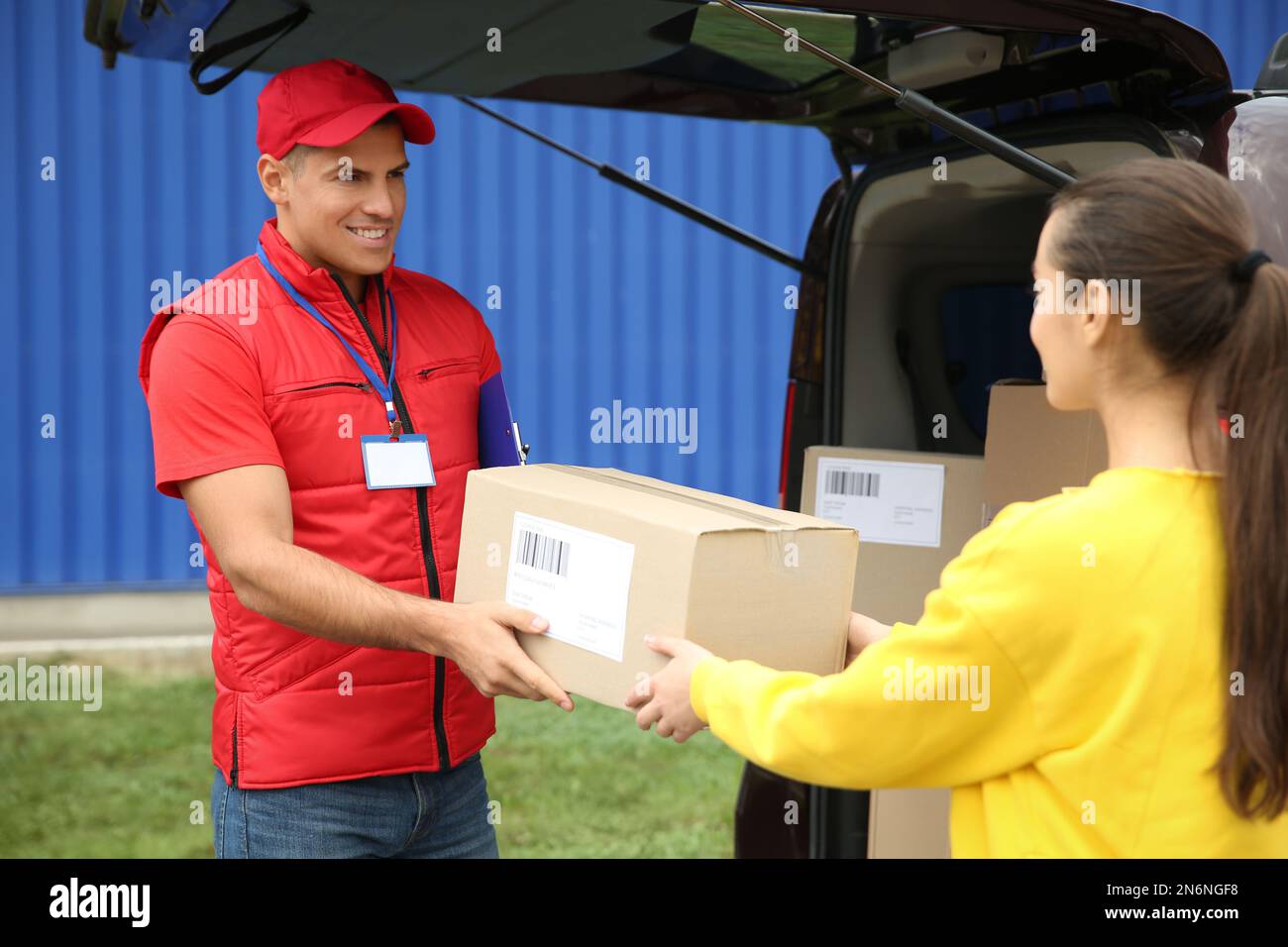 Courier giving package to customer on street Stock Photo - Alamy