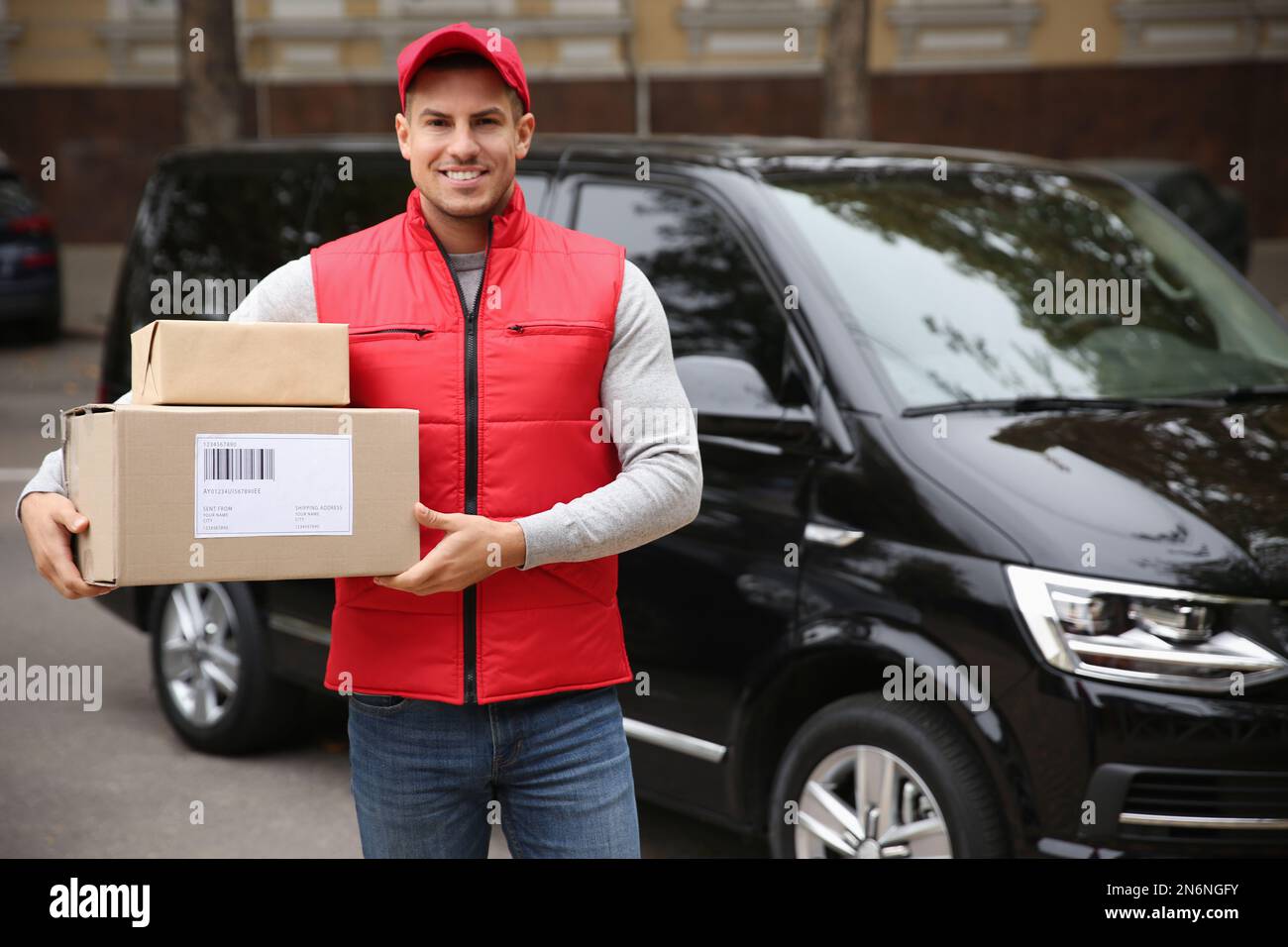 Courier with parcels near delivery van outdoors Stock Photo - Alamy