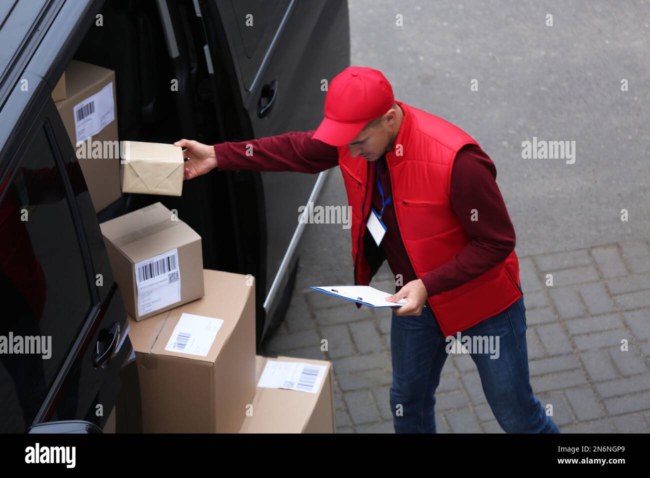 Courier checking amount of parcels in delivery van outdoors Stock Photo ...