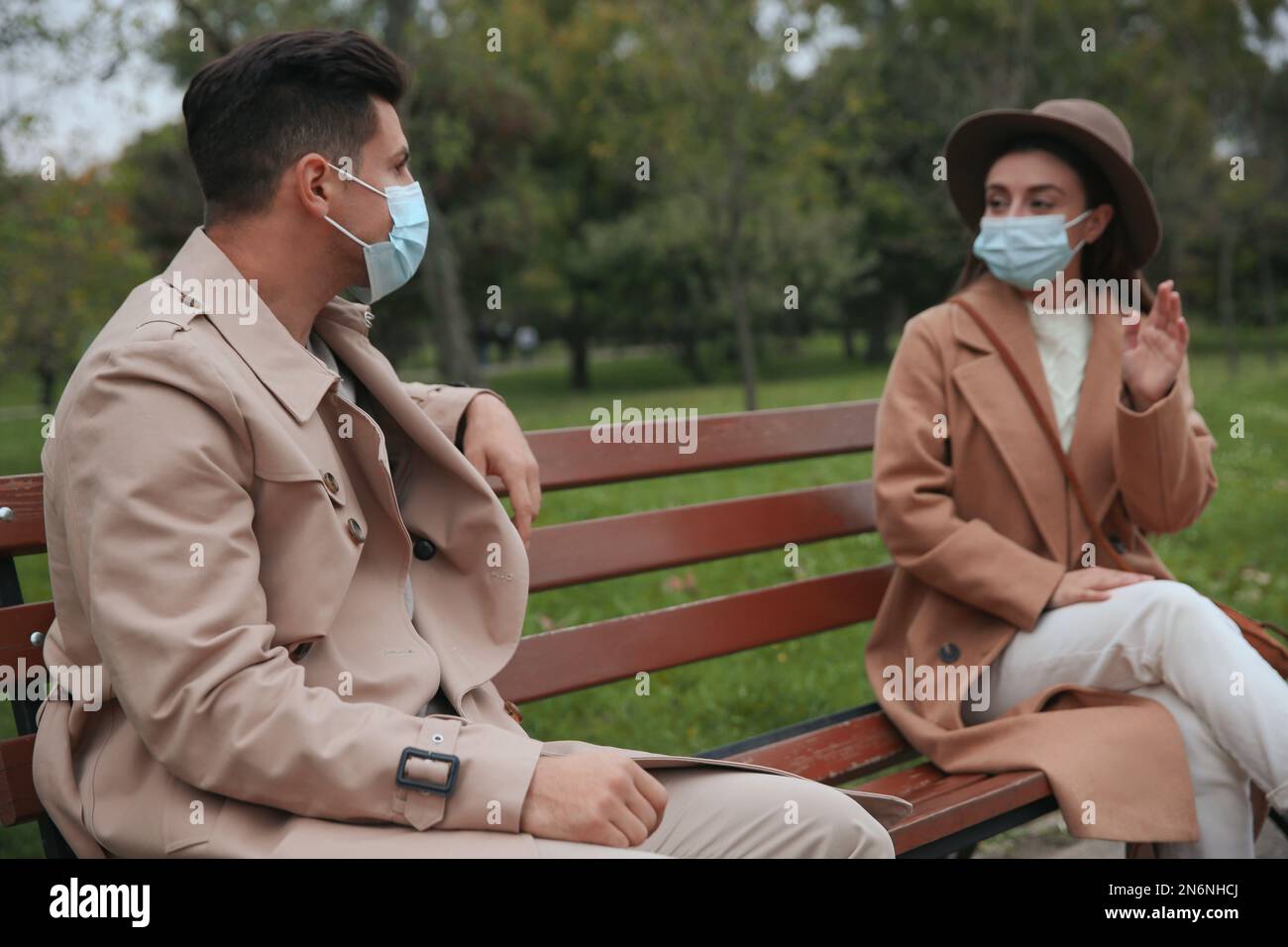 Man and woman talking on bench in park. Keeping social distance during ...