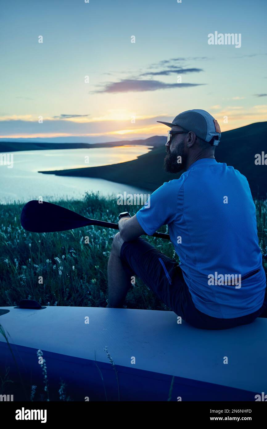 Portrait of bearded Man in silhouette holding SUP board paddle near ...
