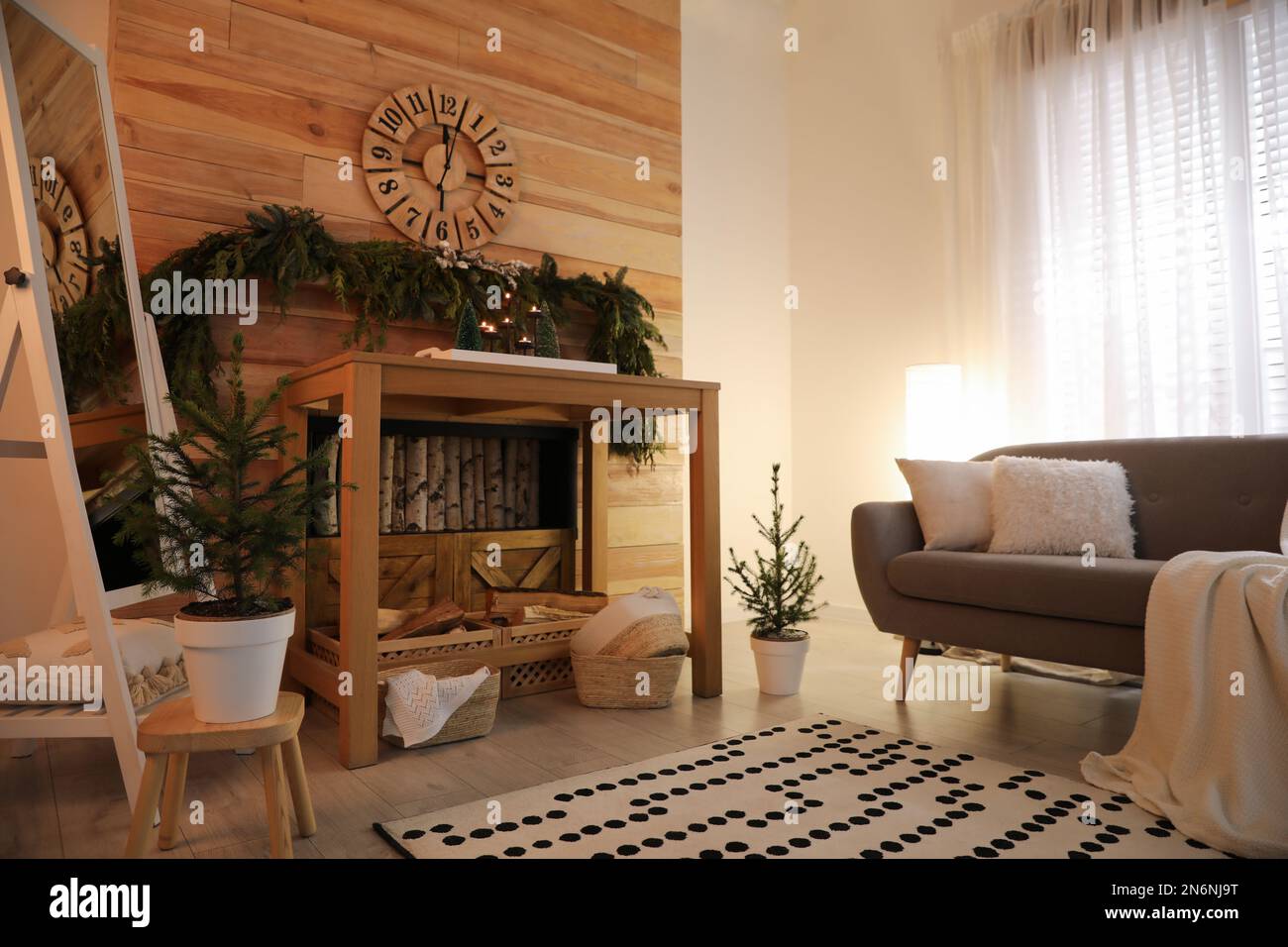 Cozy room interior with console table and conifer garland near wooden ...