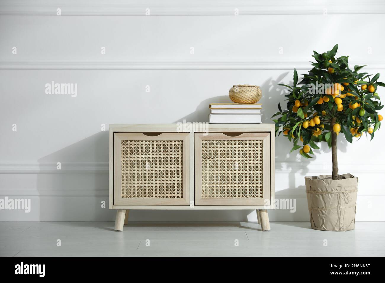 Wooden commode near white wall in room. Interior design Stock Photo - Alamy