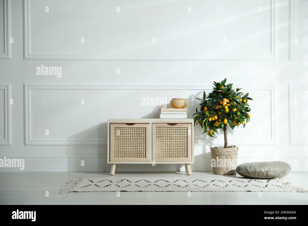 Wooden commode near white wall in room. Interior design Stock Photo - Alamy