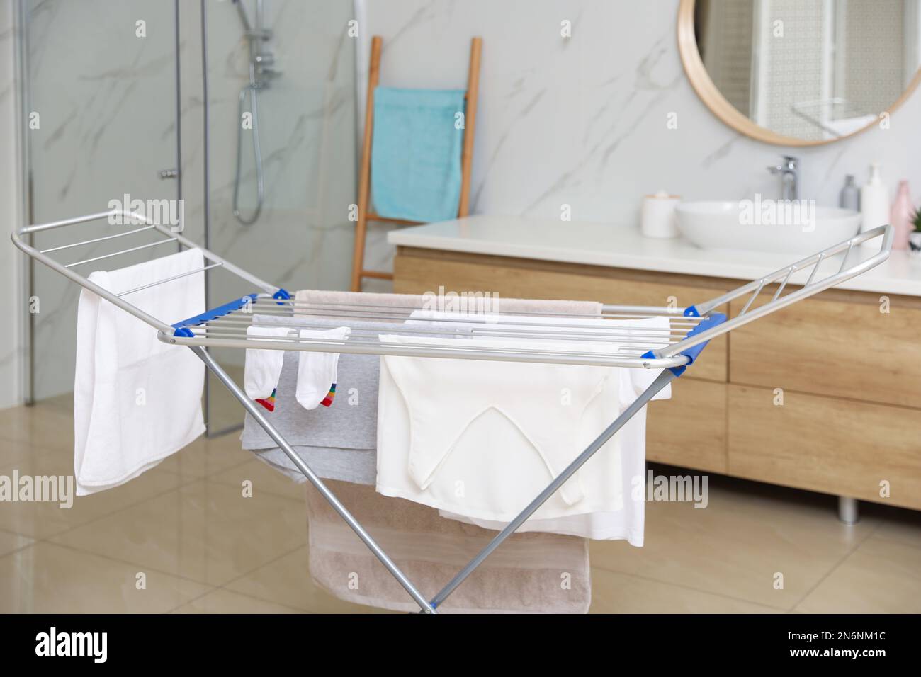 Clean laundry hanging on drying rack in bathroom Stock Photo - Alamy