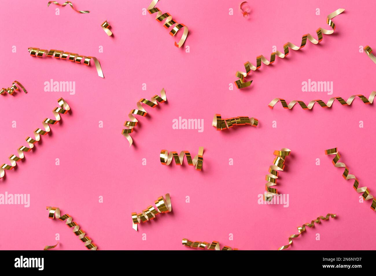 Shiny golden serpentine streamers on pink background, flat lay Stock ...