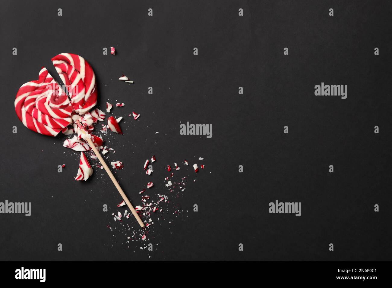 Broken heart shaped lollipop on black background, top view with space ...