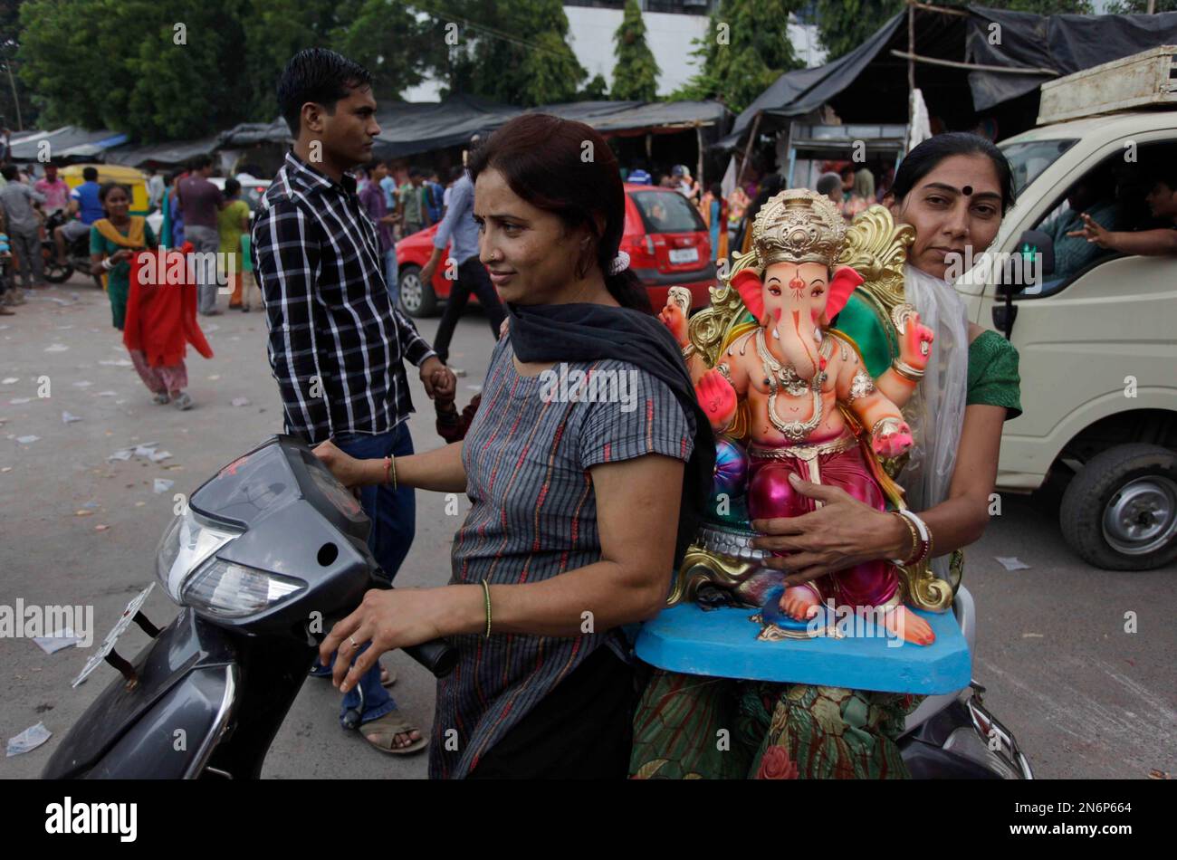 Indian women on a two wheeler carry idols of elephant headed Hindu god ...