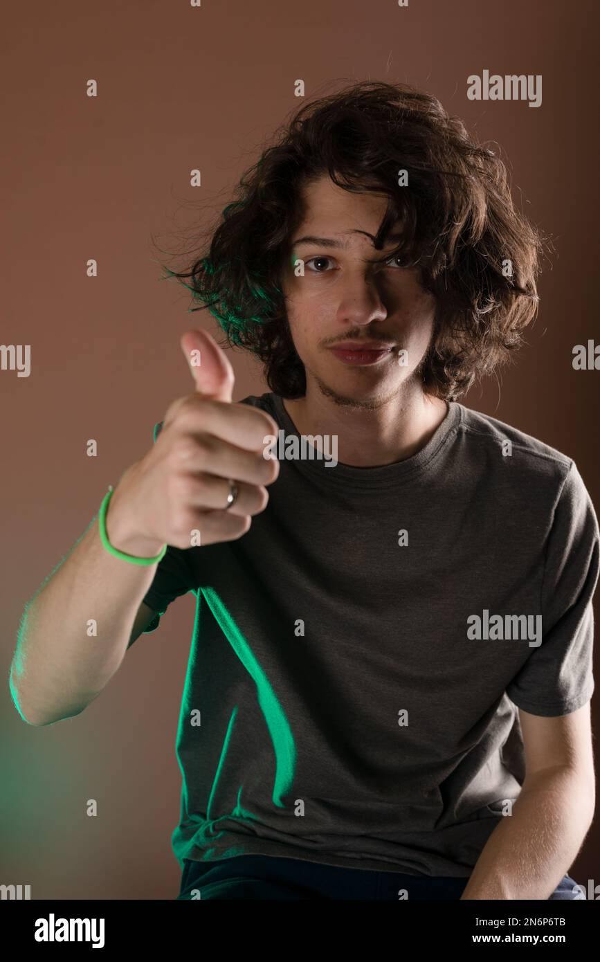 Handsome young man making thumbs up sign. Isolated Bisque background ...