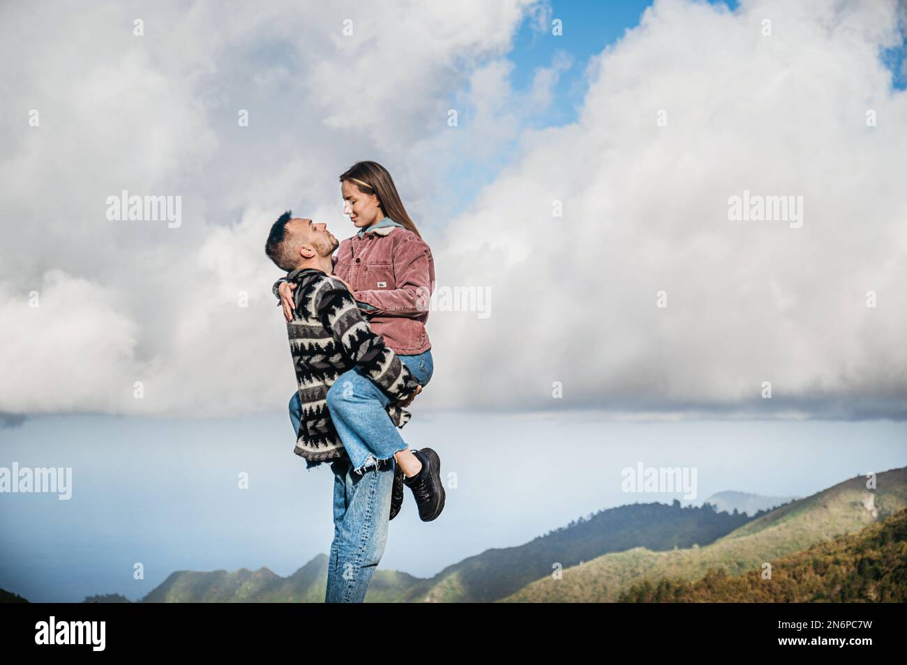 Couple in a stunning landscape, man holds the woman as she wraps her ...