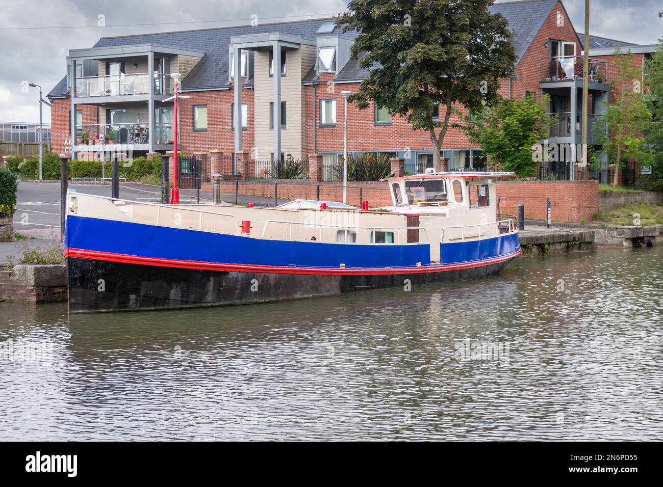 A dutch barge style canal boat painted white red blue and black moored ...