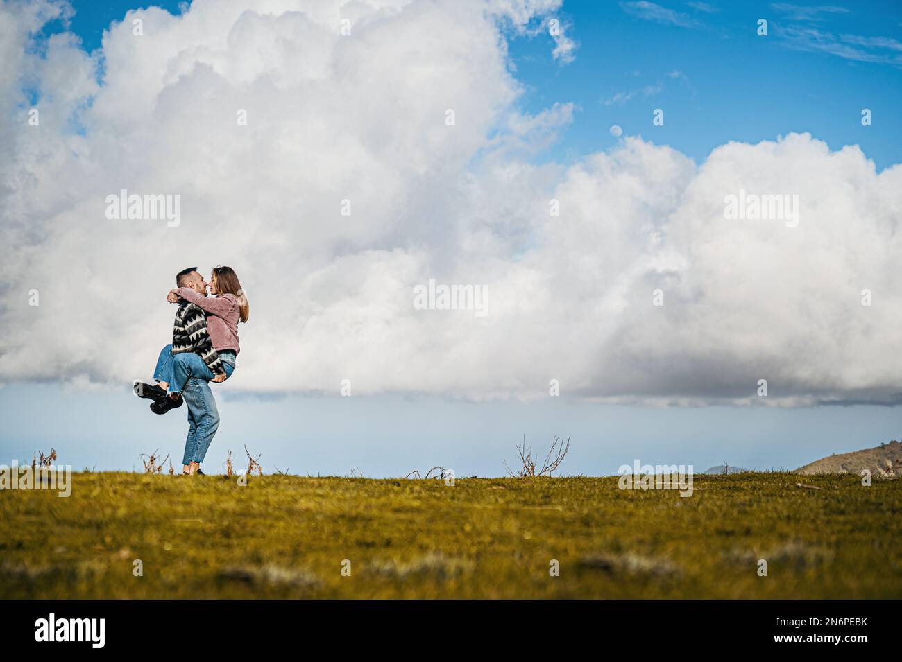 Couple in a stunning landscape, man holds the woman as she wraps her ...