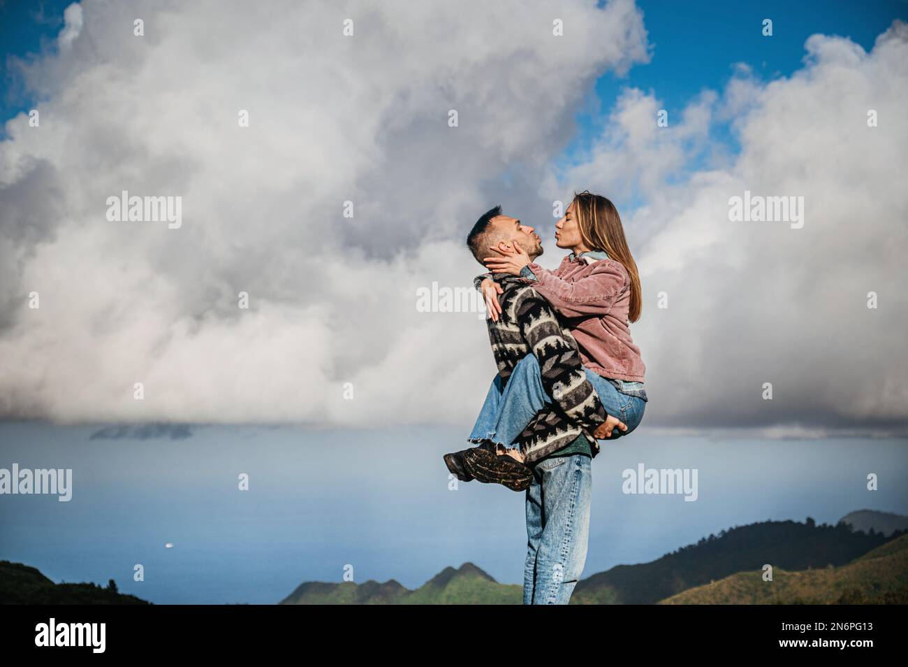 Couple in a stunning landscape, man holds the woman as she wraps her ...