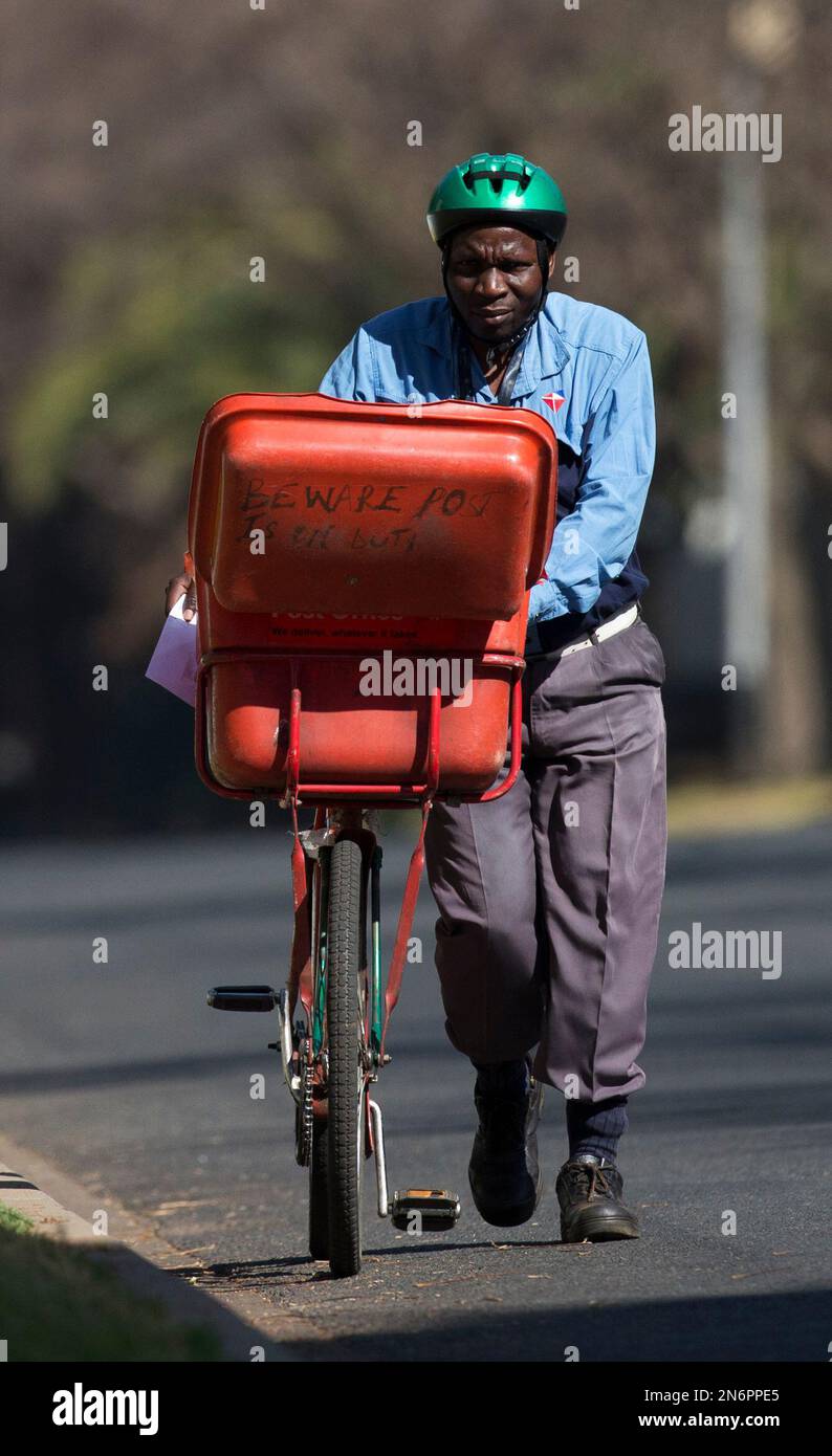 A postman pushes his bicycle up a hill in front of former South African ...