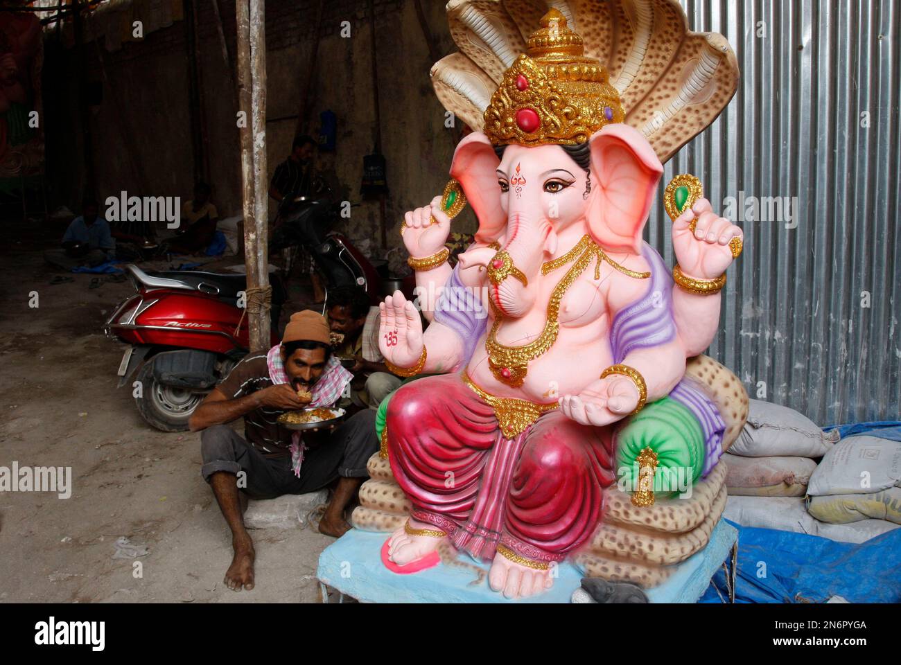 An Indian artisan eats a meal near an idol of elephant-headed Hindu God Ganesha being prepared ...
