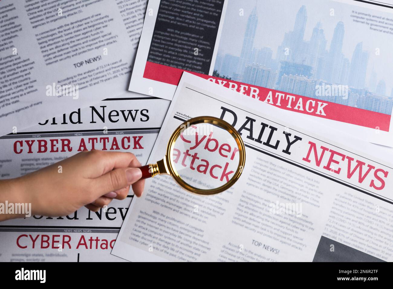 Woman using magnifying glass to read newspaper with headline CYBER ...