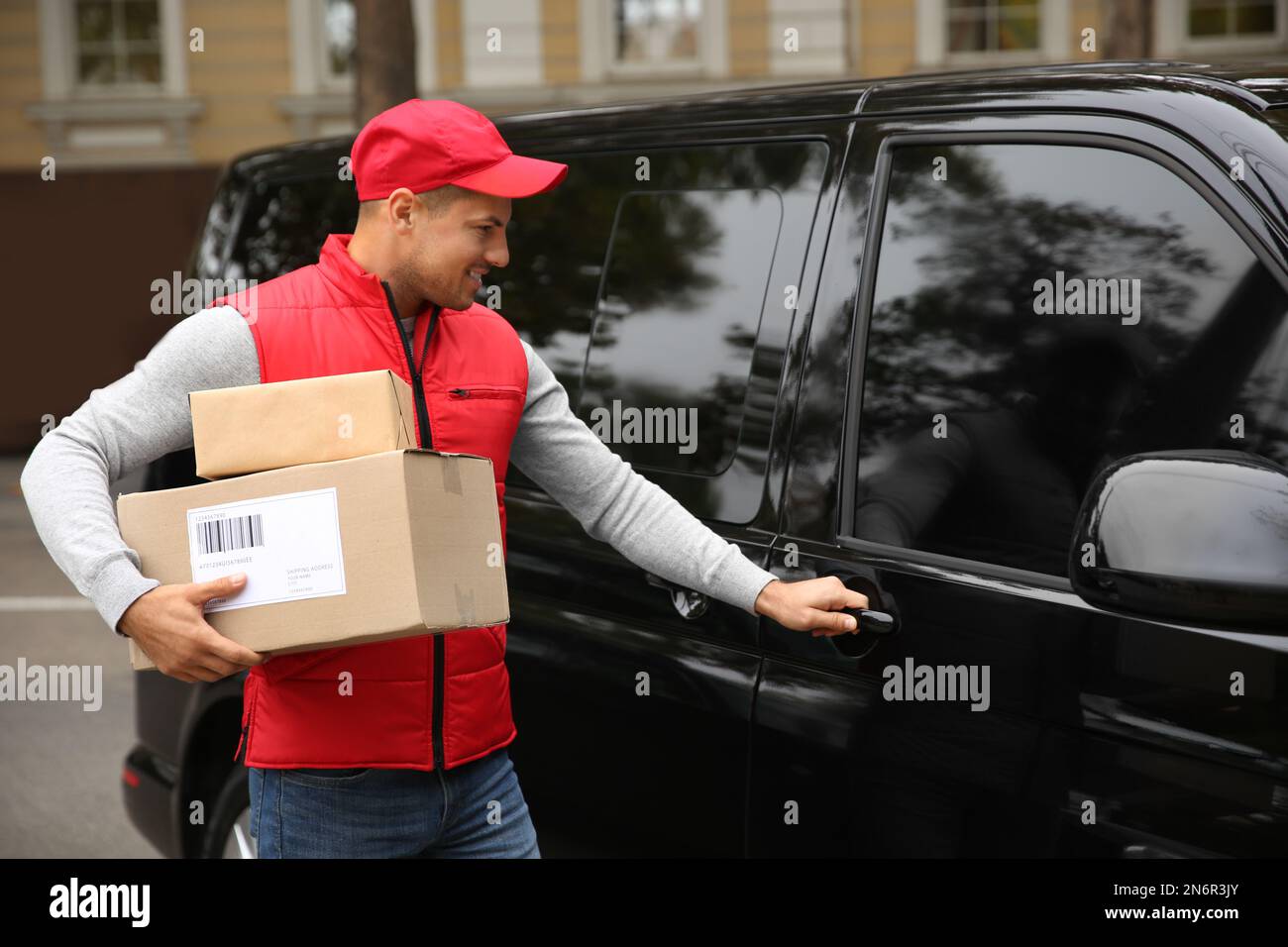 Courier with parcels near delivery van outdoors Stock Photo - Alamy