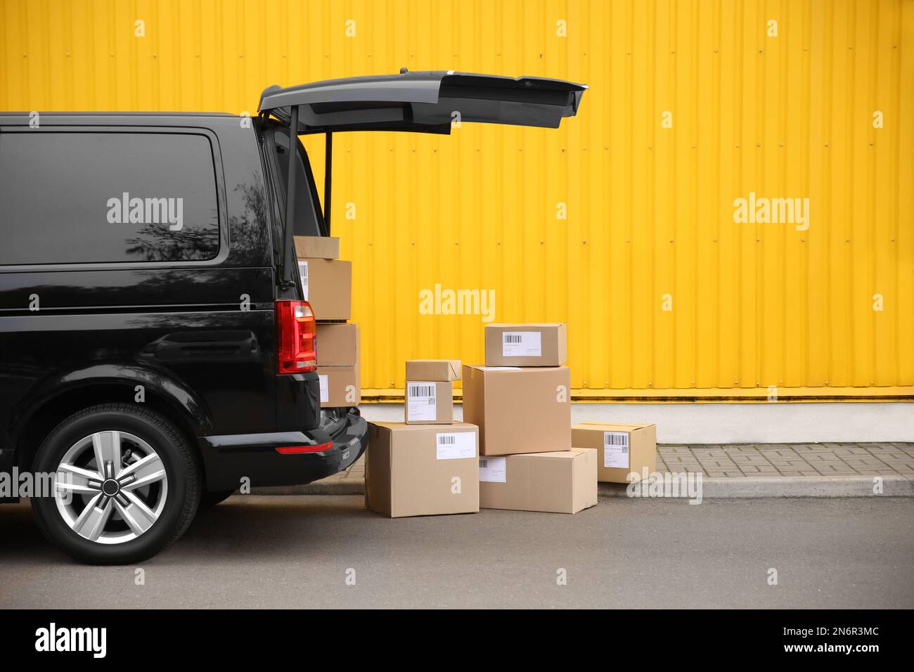 Black delivery van and many different parcels near yellow building ...