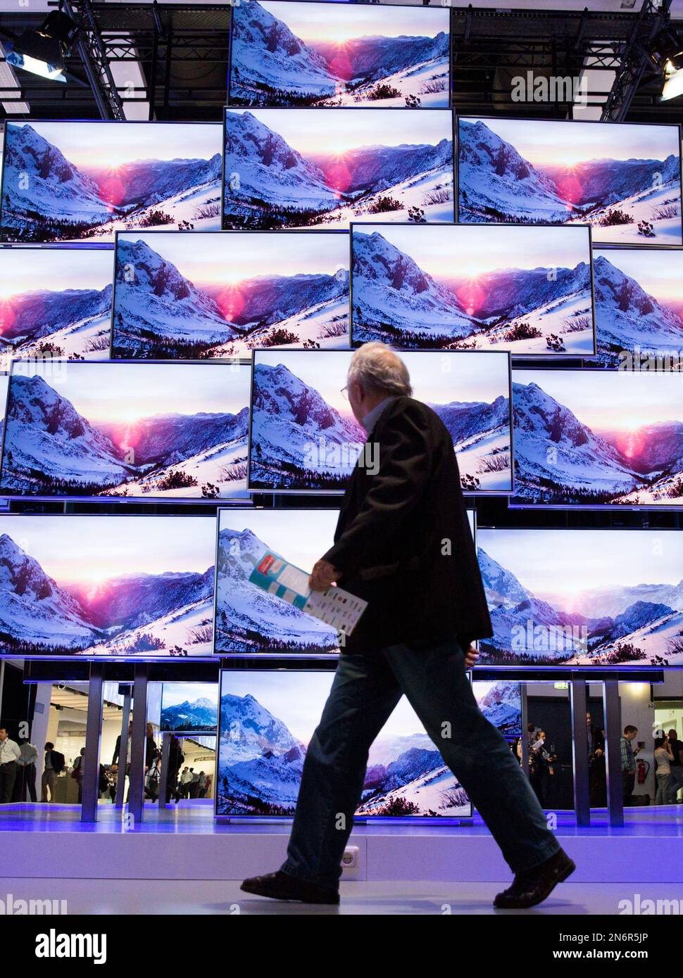 A man passes huge Ultra HD 4K television screens at the booth of ...