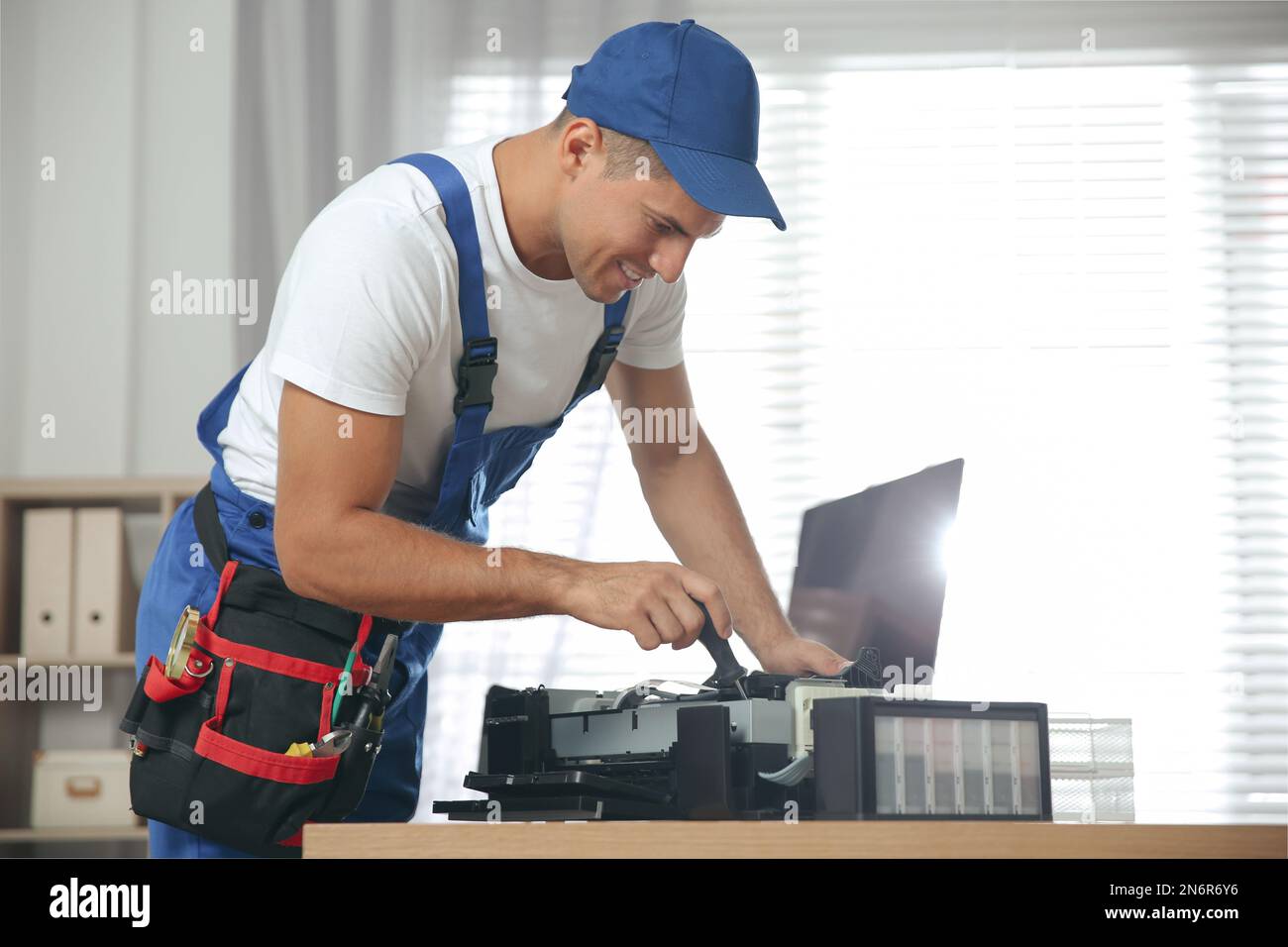 Repairman with screwdriver fixing modern printer in office Stock Photo ...