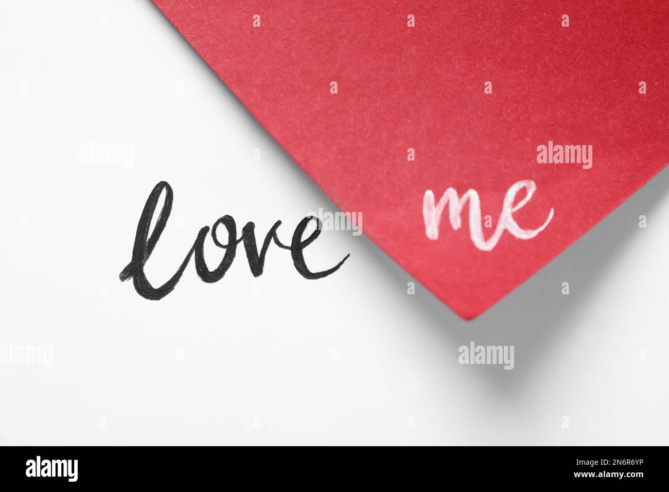 Phrase Love Me written on white and red paper Stock Photo - Alamy
