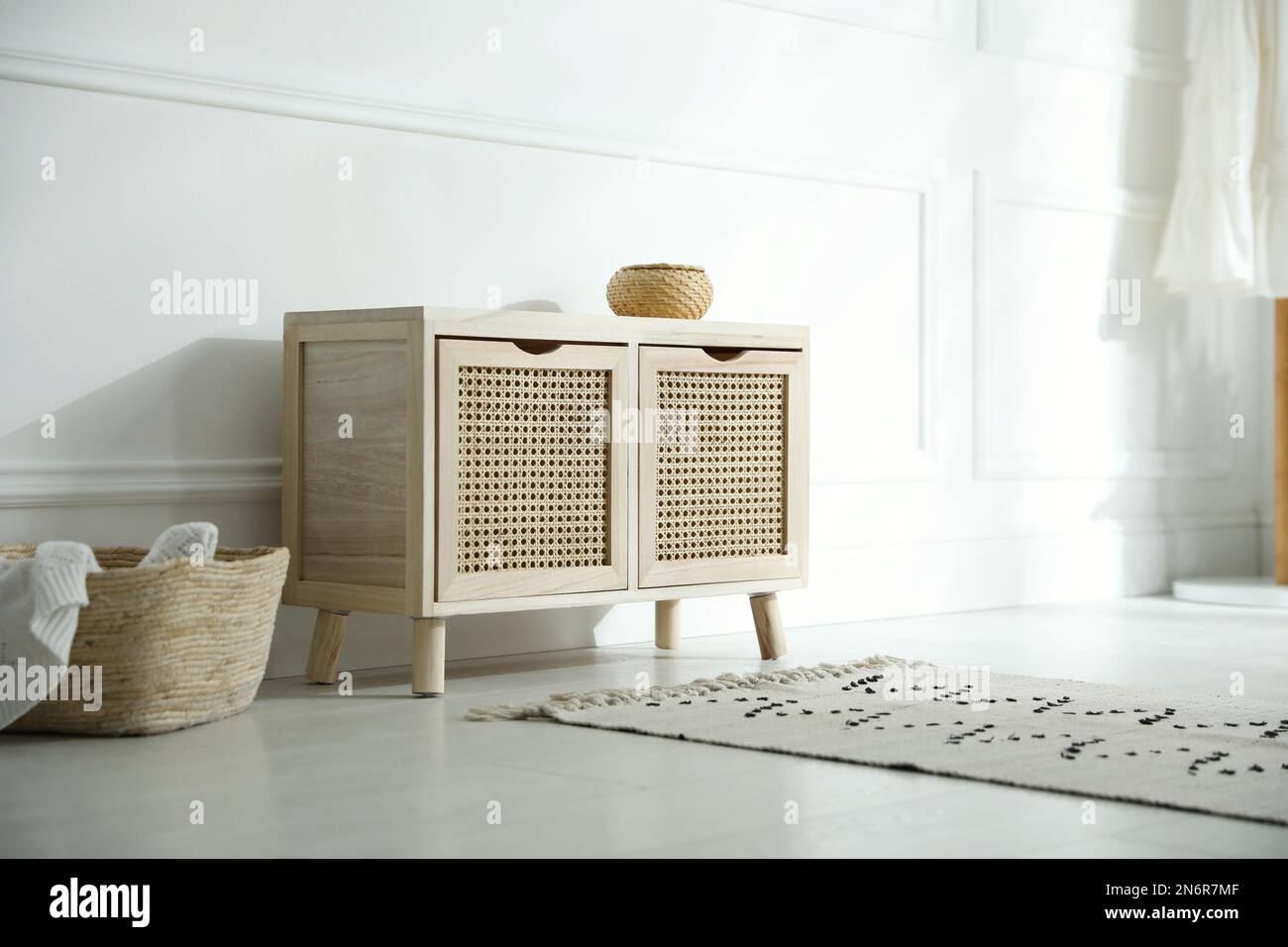 Wooden commode near white wall in room. Interior design Stock Photo - Alamy