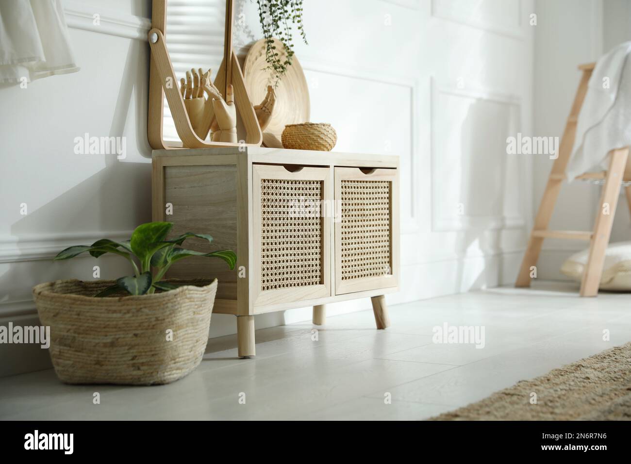 Wooden commode near white wall in room. Interior design Stock Photo - Alamy