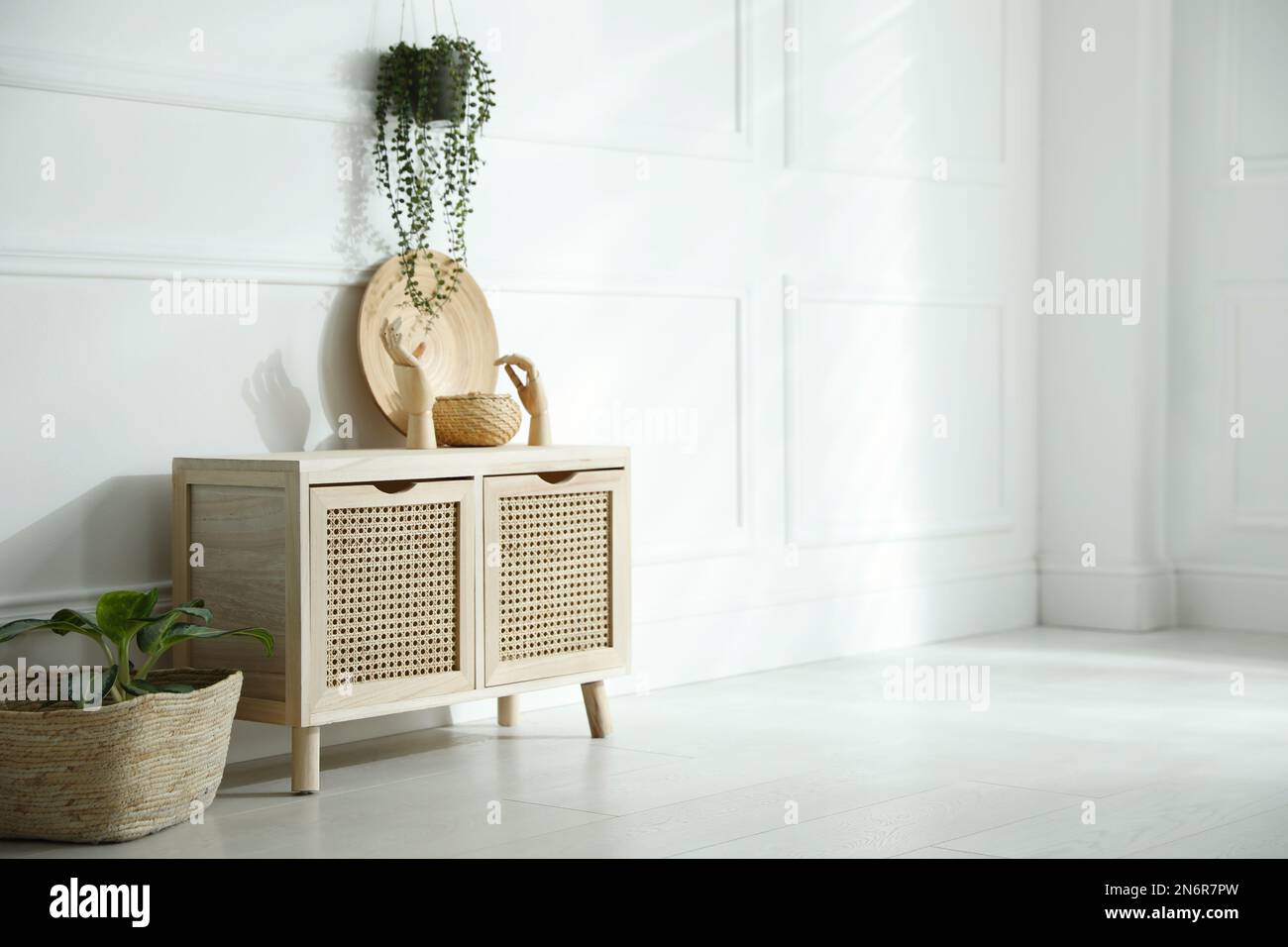 Wooden commode near white wall in room. Interior design Stock Photo - Alamy
