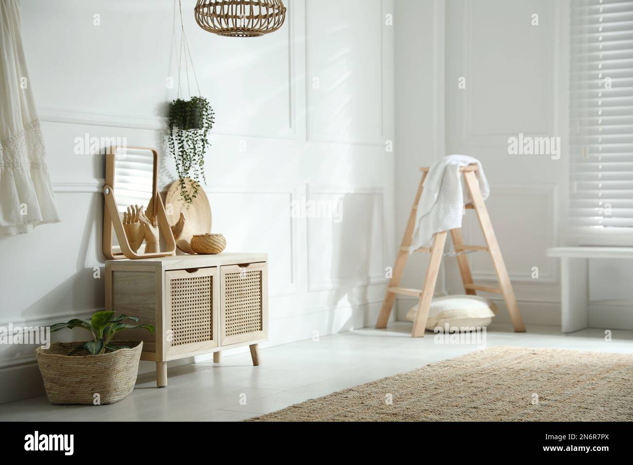 Wooden commode near white wall in room. Interior design Stock Photo - Alamy