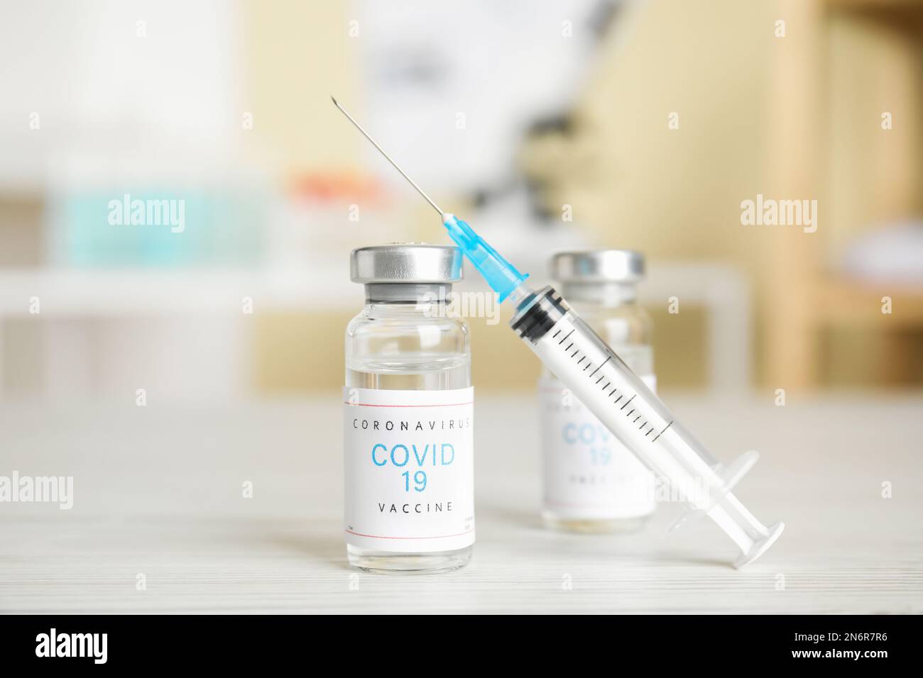 Vials with vaccine against Covid-19 and syringe on white table indoors ...
