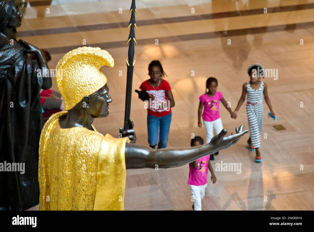 Young tourists walk beneath the towering bronze statue of King ...