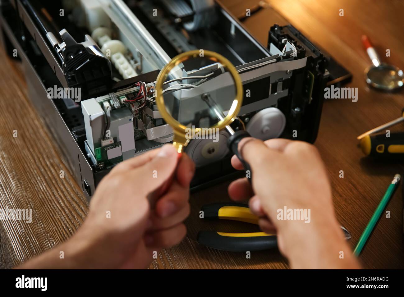 Repairman with magnifying glass and screwdriver fixing modern printer ...