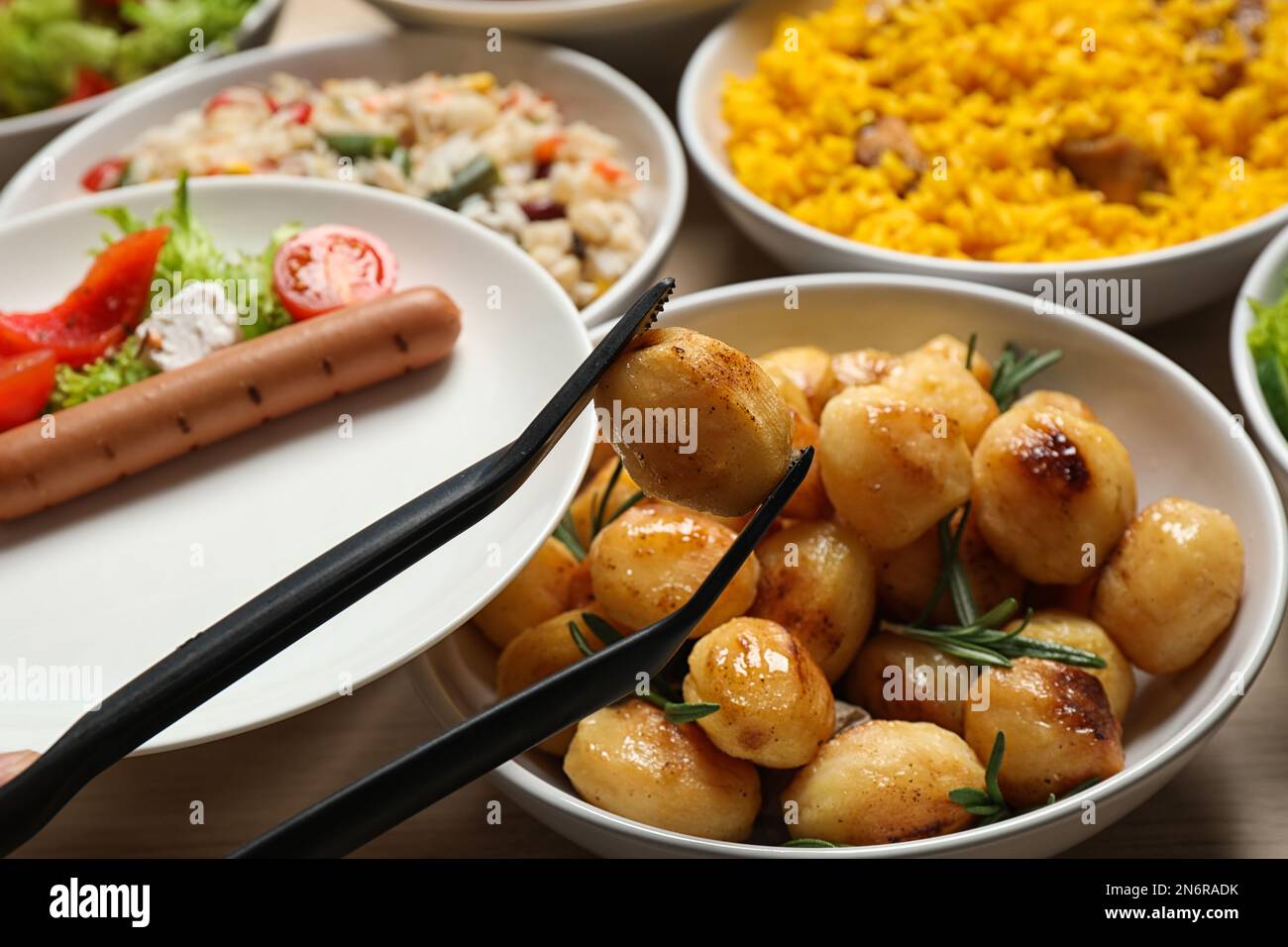 Taking roasted potato from buffet table, closeup Stock Photo - Alamy