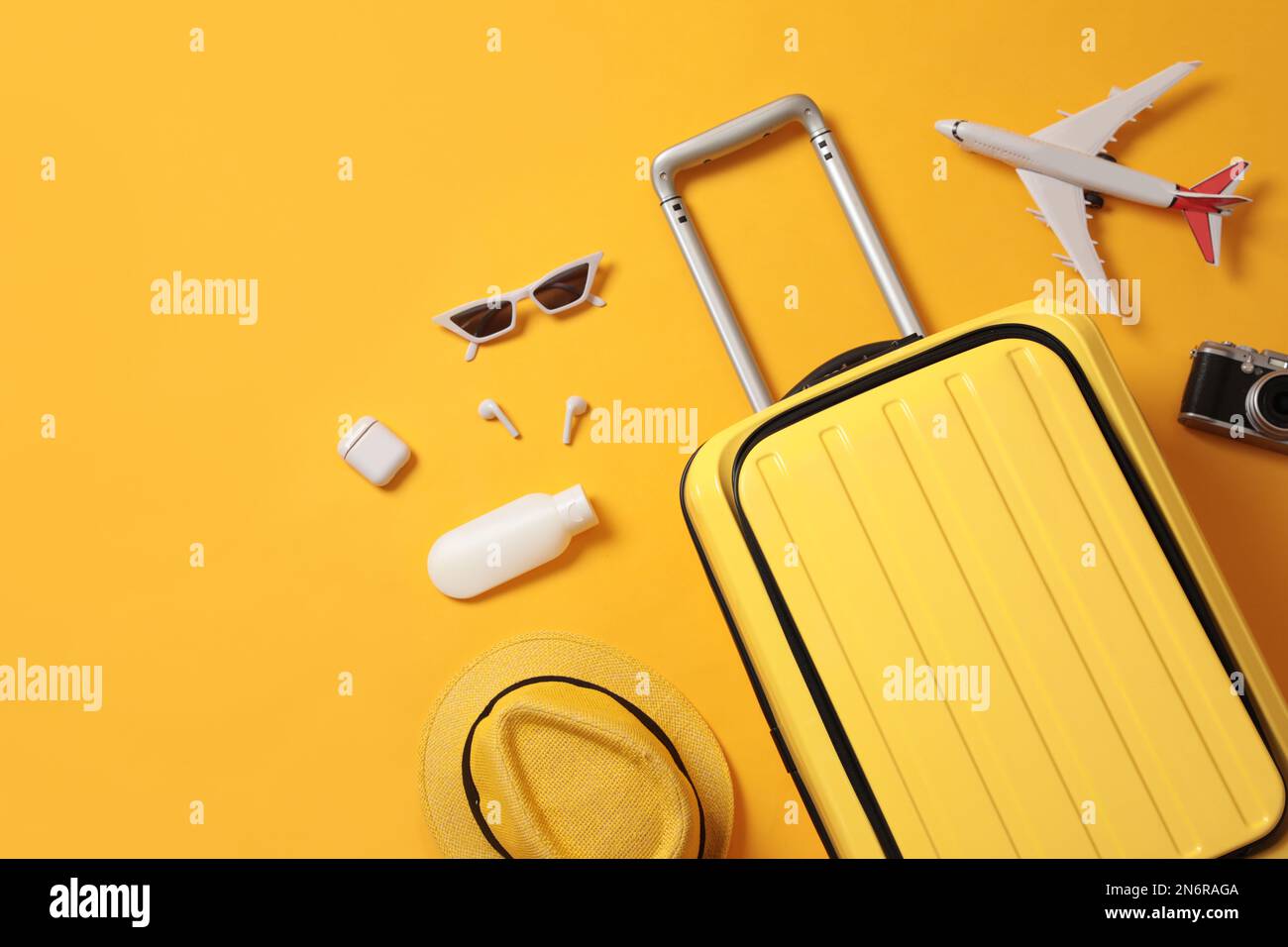 Flat lay composition with suitcase and travel accessories on yellow ...