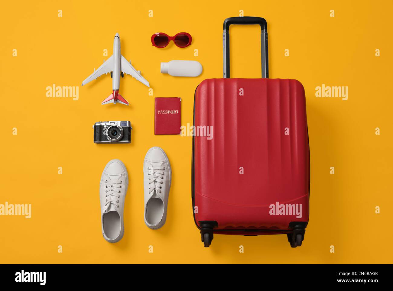 Flat lay composition with suitcase and travel accessories on yellow ...