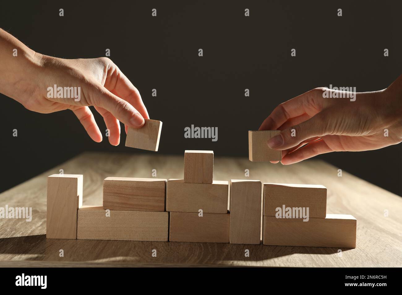 People constructing with wooden building blocks, closeup. Corporate ...