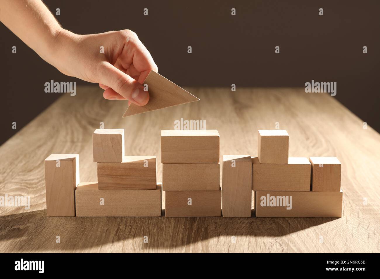 Woman constructing with wooden building blocks, closeup. Corporate ...