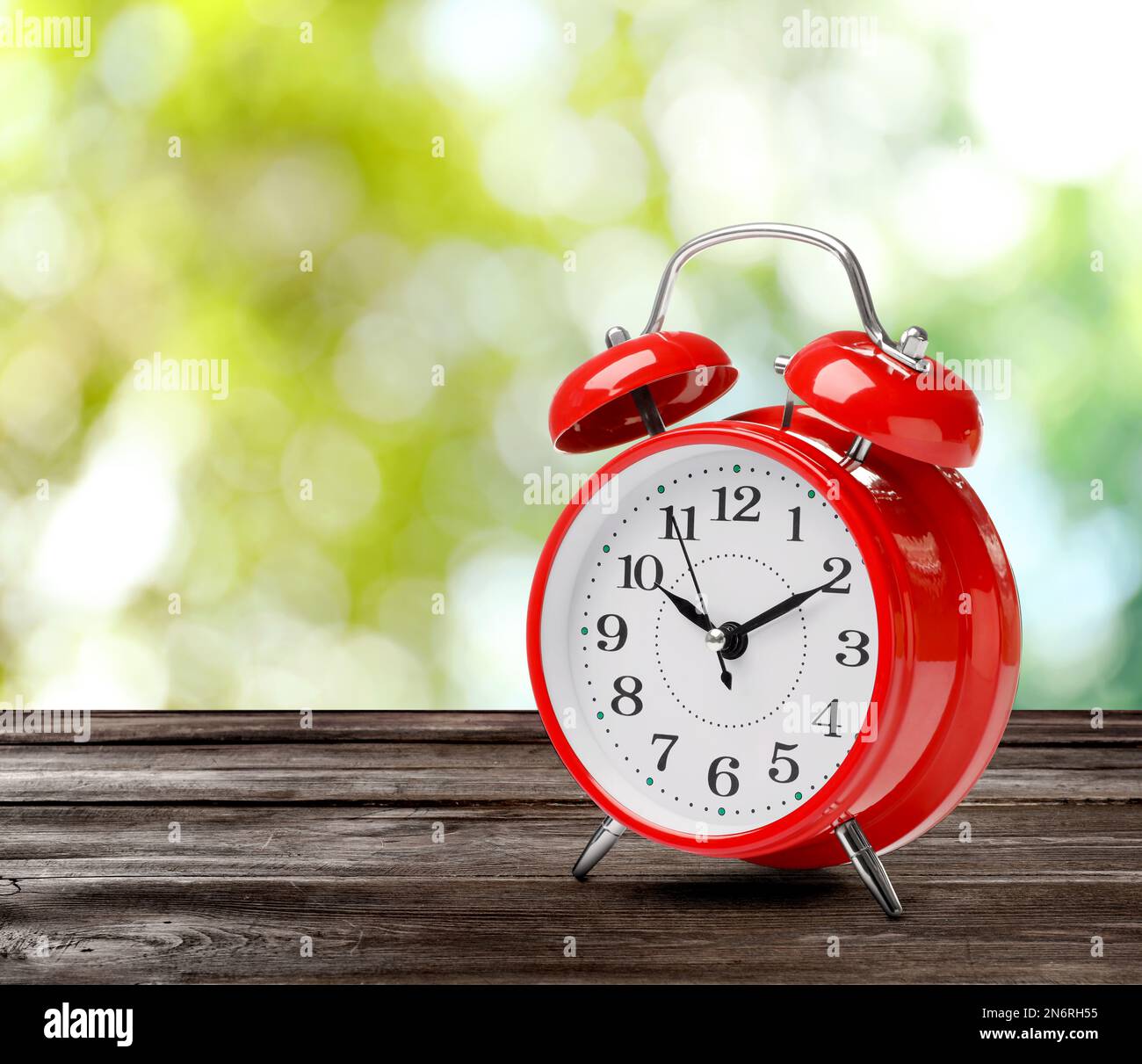 Red alarm clock on wooden table, space for text. Daylight saving time ...