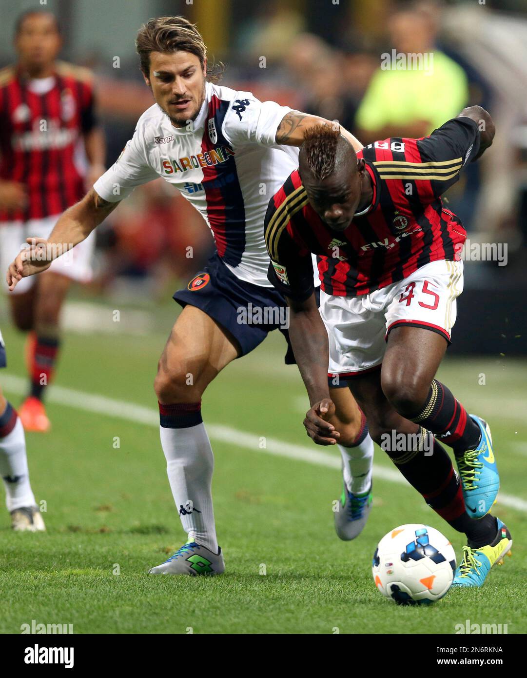 AC Milan forward Mario Balotelli, right, is challenged by Cagliari midfielder Daniele Dossena ...