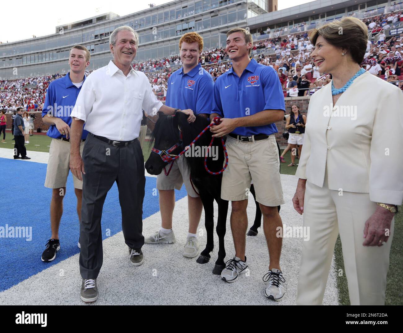 Former President George W. Bush, left, pets the SMU mascot as his wife ...