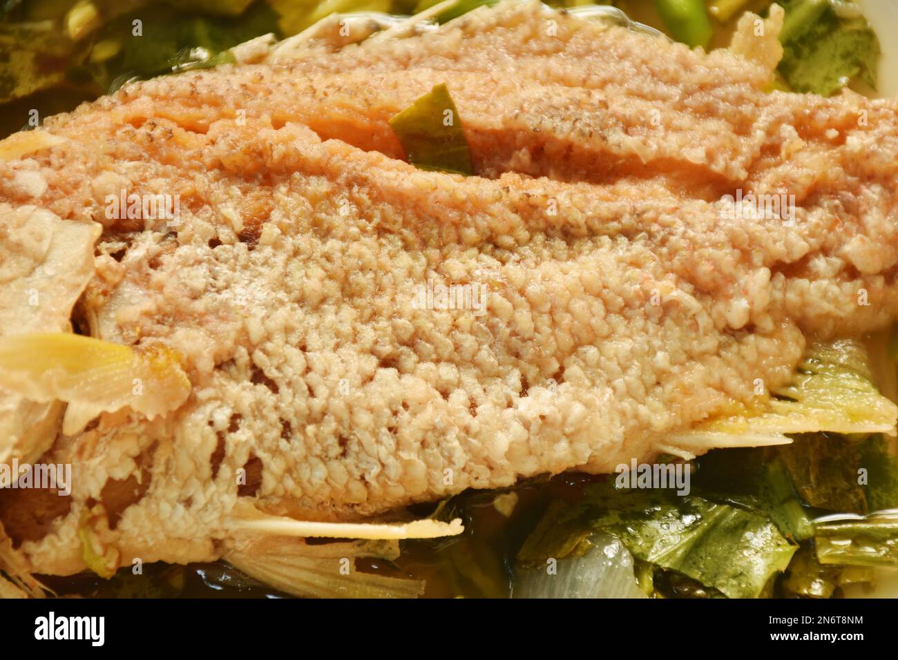 spicy boiled fried red bass fish and herb in tom yum soup on plate ...