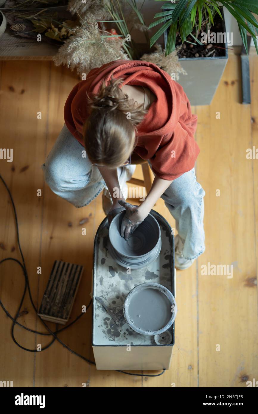 Top view of concentrated woman making handmade utensils sits at pottery ...