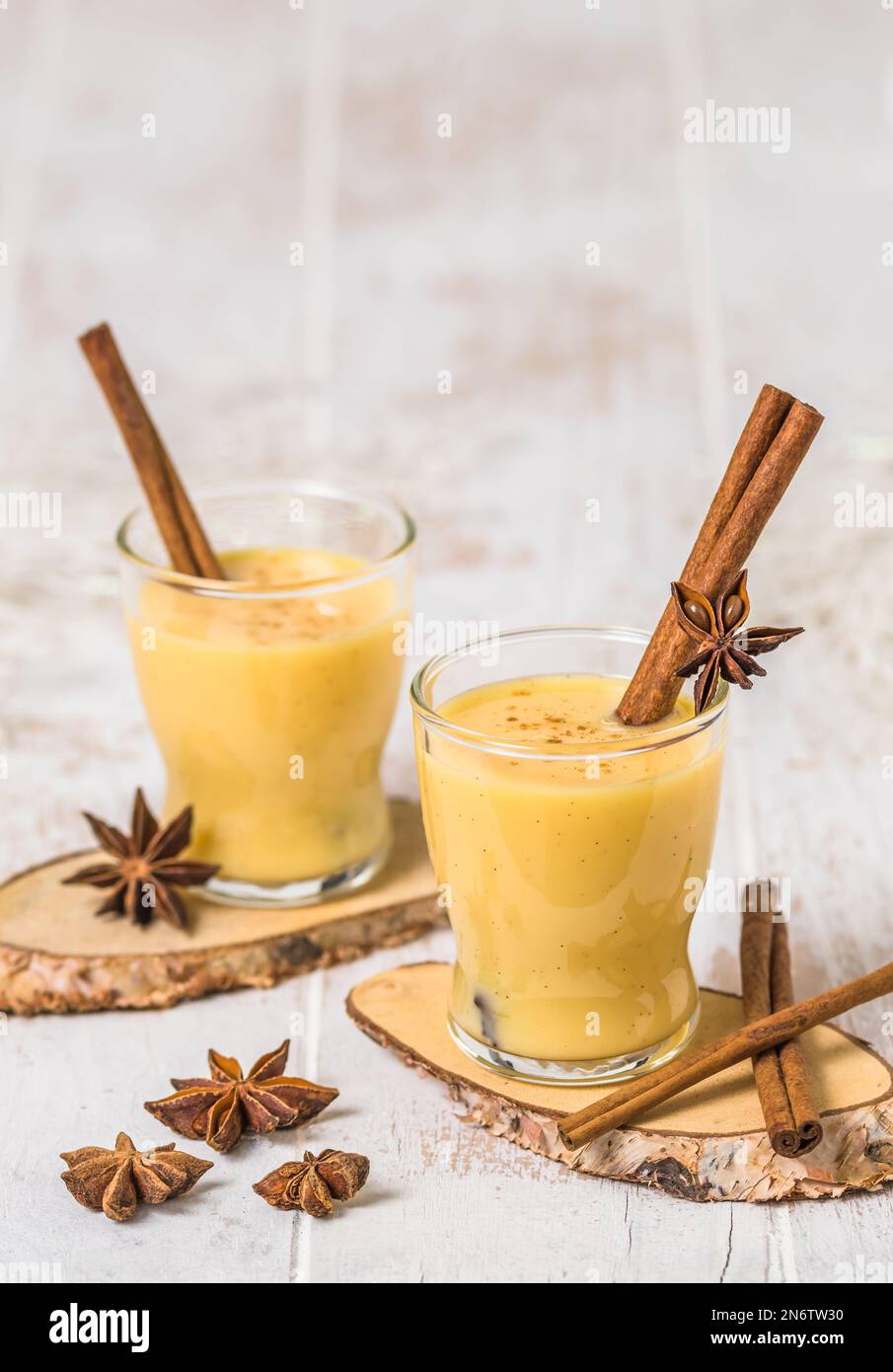 Two glasses of eggnogg with cinnamon sticks on white wooden background ...