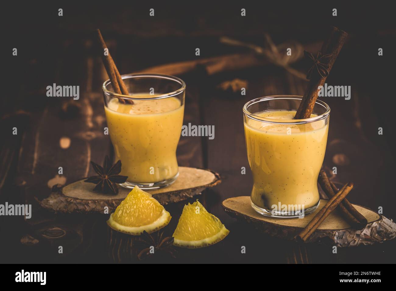 Two glasses of eggnogg with cinnamon sticks on dark wooden background ...