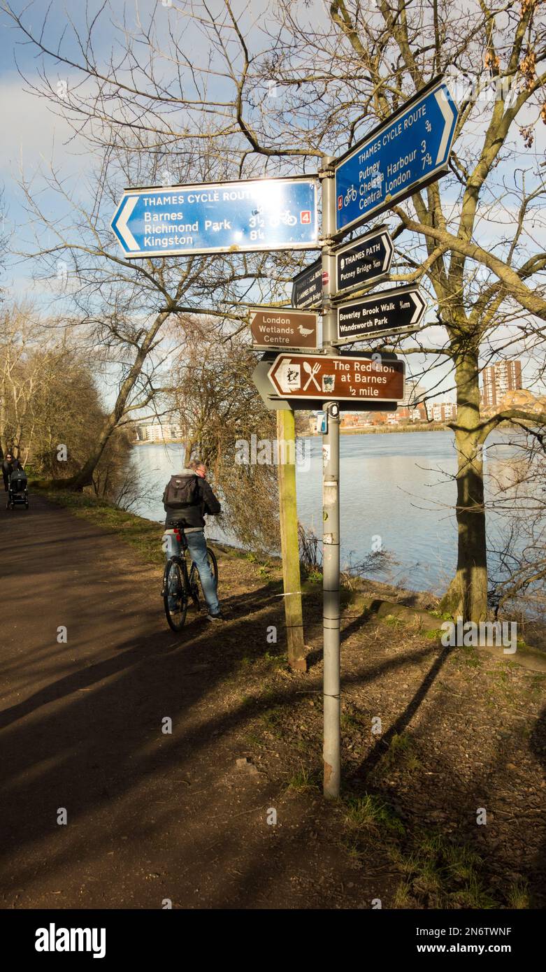 A cyclist resting next to Thames Cycle Route signage on the Thames Path ...