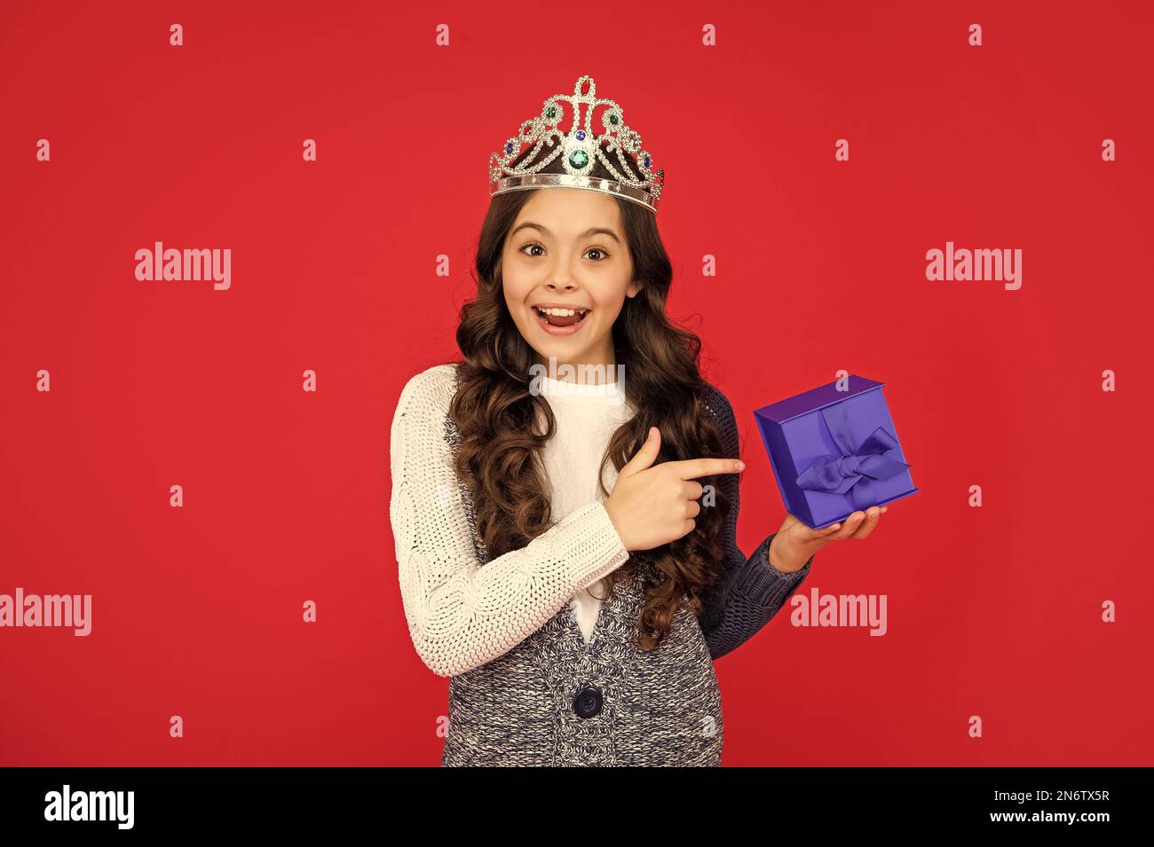 surprised child in queen crown. princess in tiara point finger on box ...