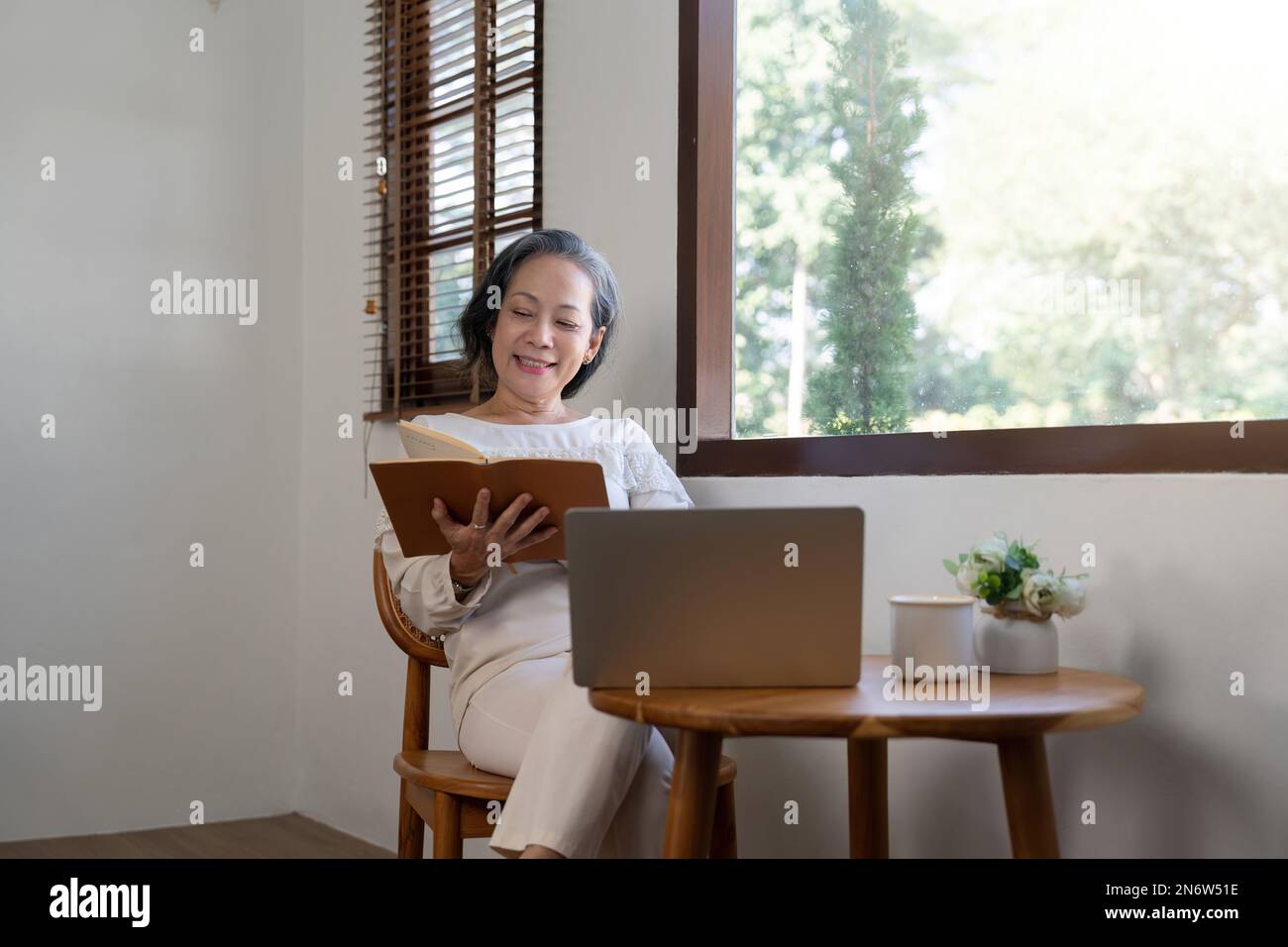 Older asian woman reading book hi-res stock photography and images - Alamy