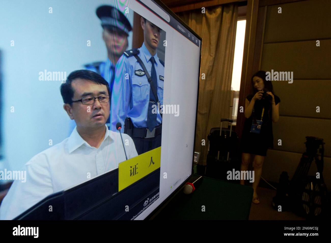 A journalist stands near a screen displaying a photo of former Chongqing city police chief Wang ...
