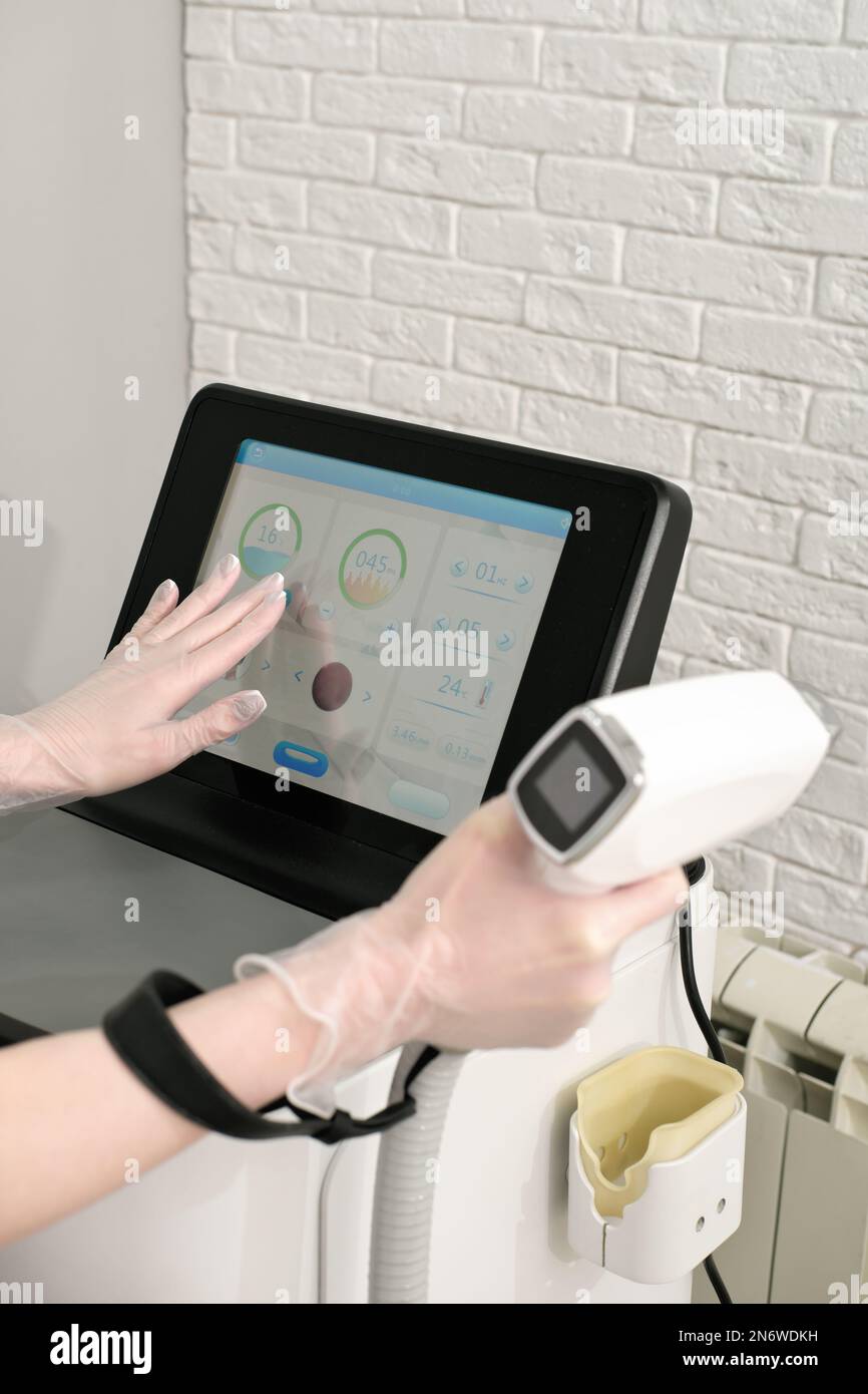 Cosmetologist's hand adjusting a modern laser epilation machine in a ...